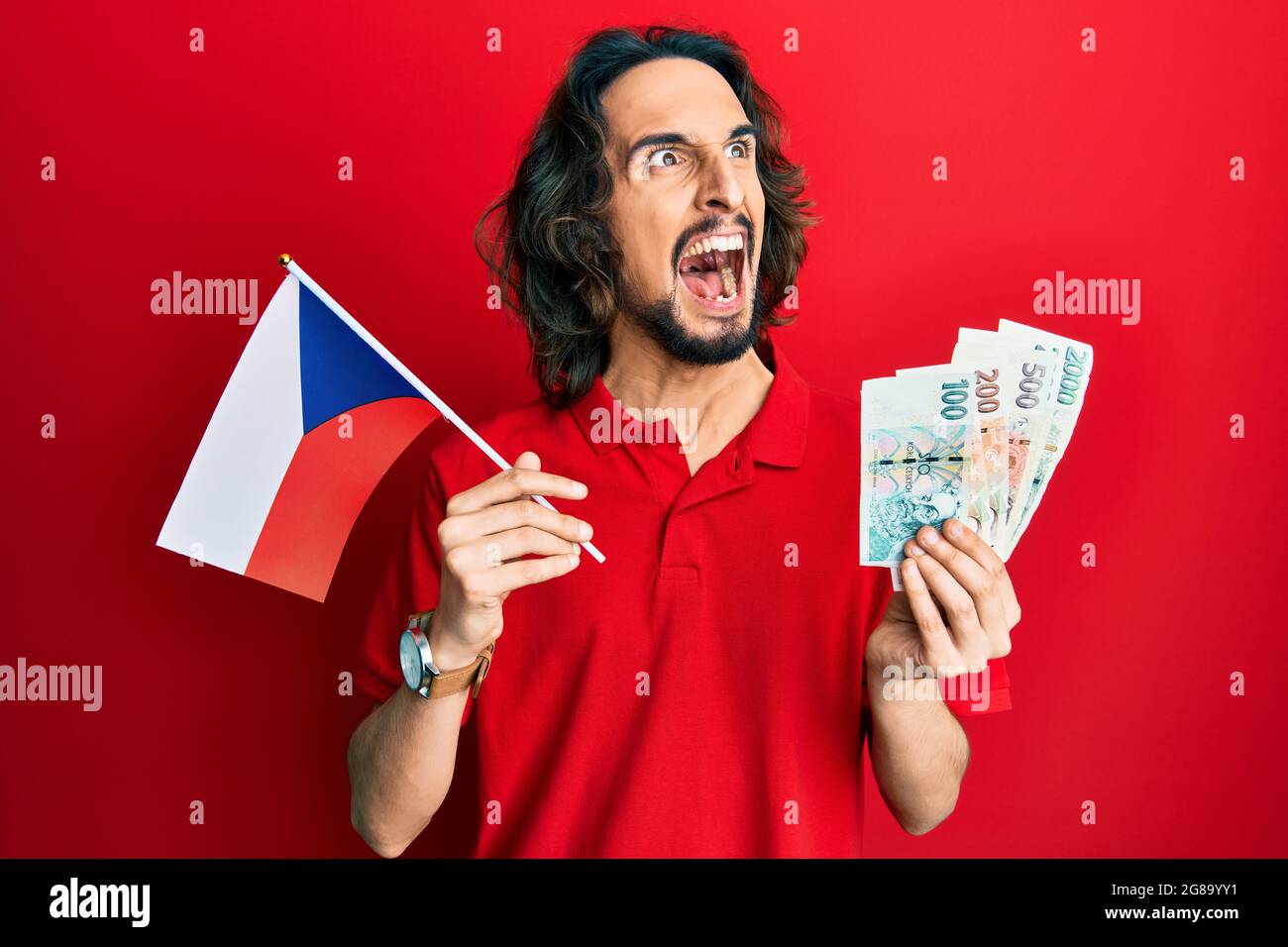 Young hispanic man holding czech republic flag and koruna banknotes ...