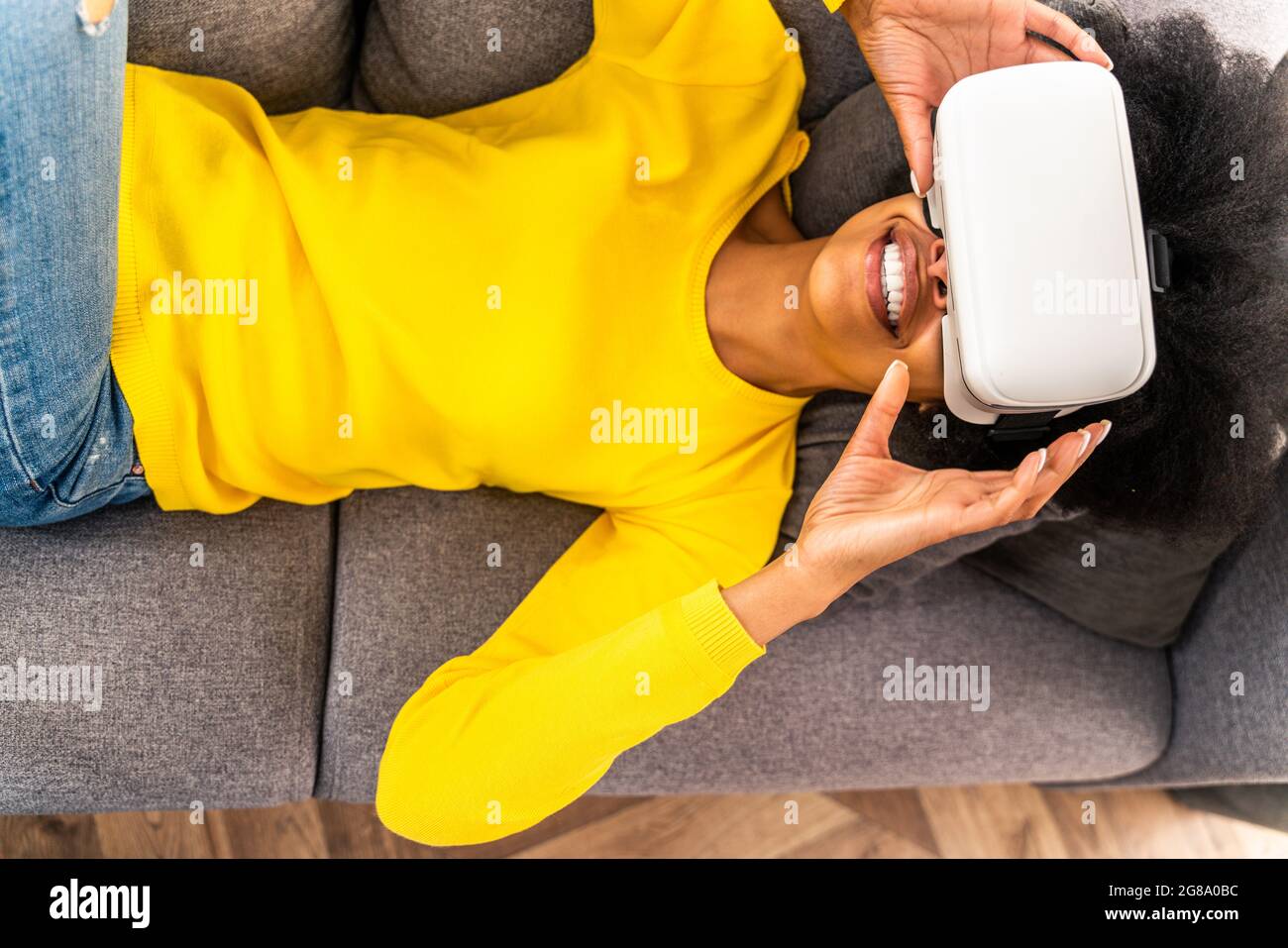 Beautiful woman playing at home with VR headset - Black woman lying ...