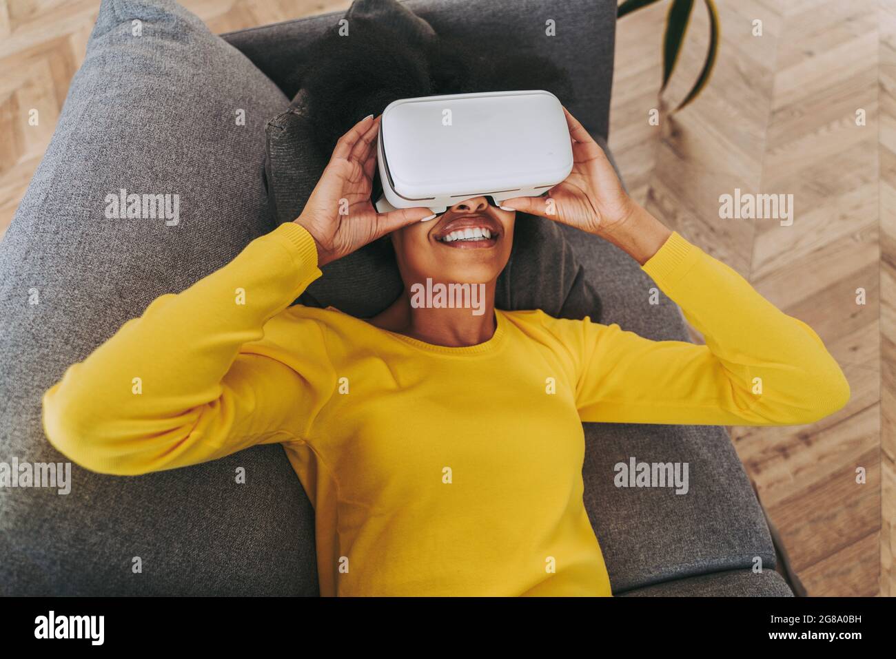 Beautiful woman playing at home with VR headset - Black woman lying ...
