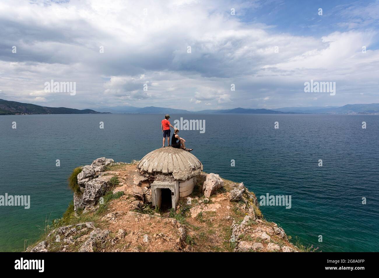 mother with her son enjoy the beautiful view while sitting on a rock by ...