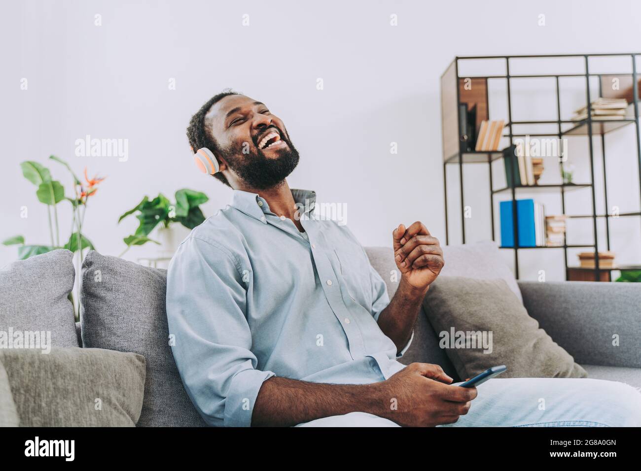 Handsome black adult man at home listening music online with smartphone ...