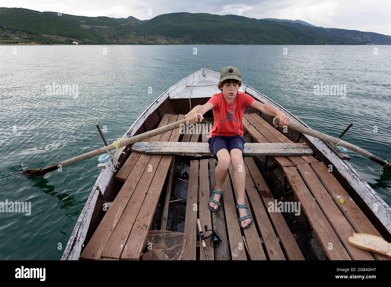 Child rowing a wooden rowboat or paddle boat on lake Ohrid, Lin ...