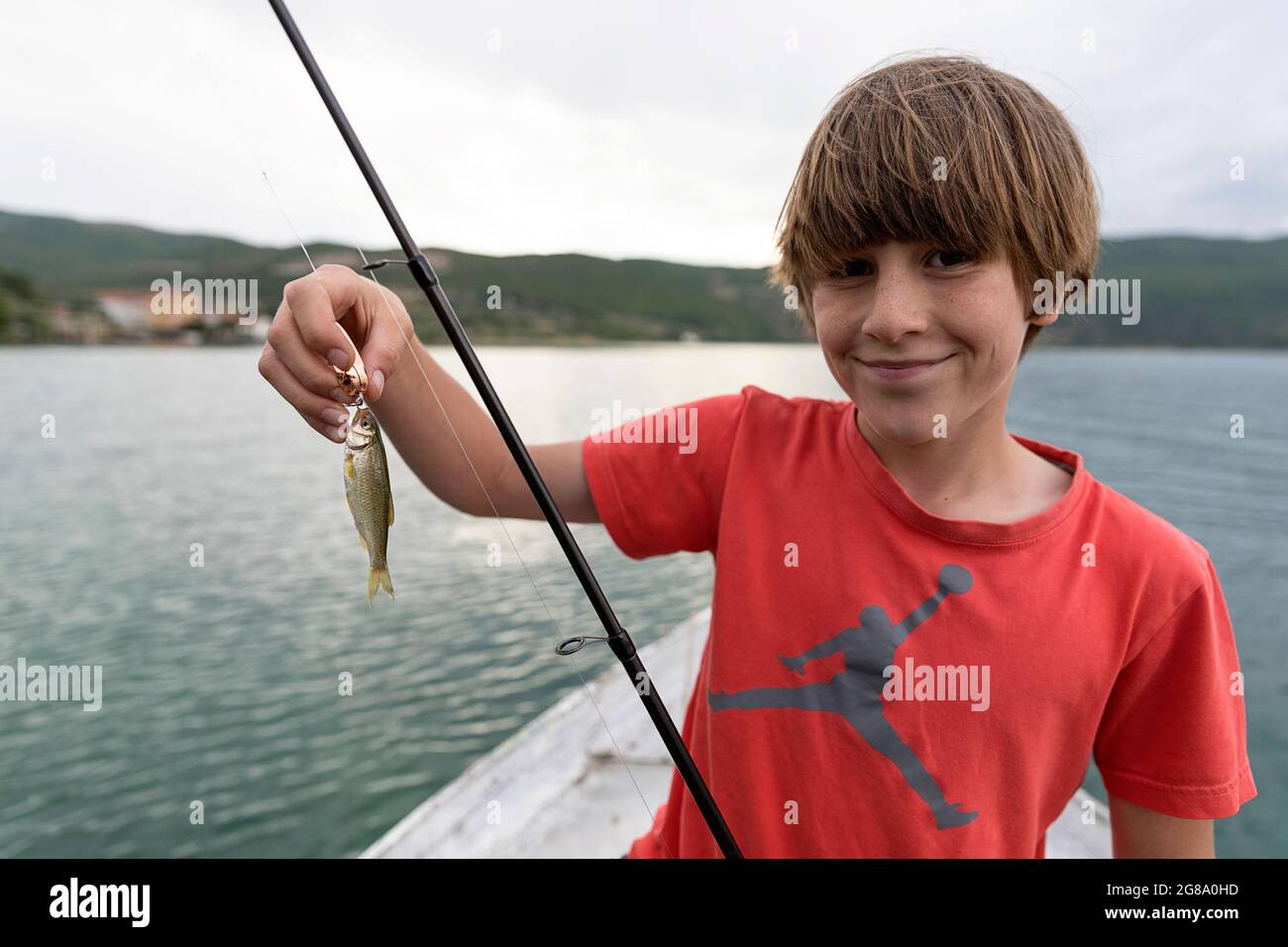 happy boy showing a fish he caught. Cute child fishing on a lake ...