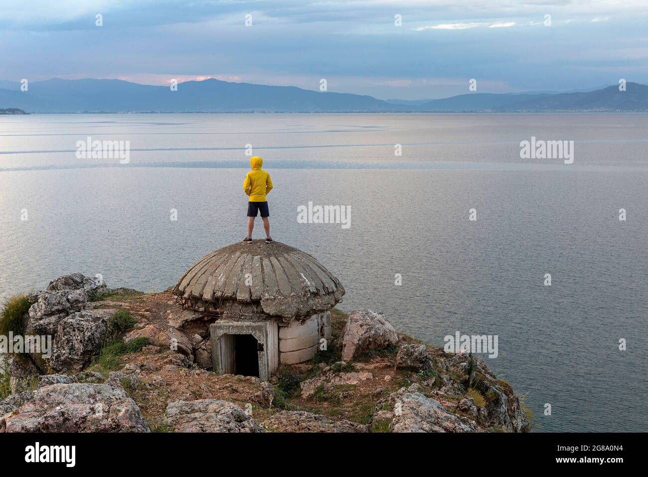 Boy standing on an old bunker at Lake Ohrid, near Lin, Korca region ...