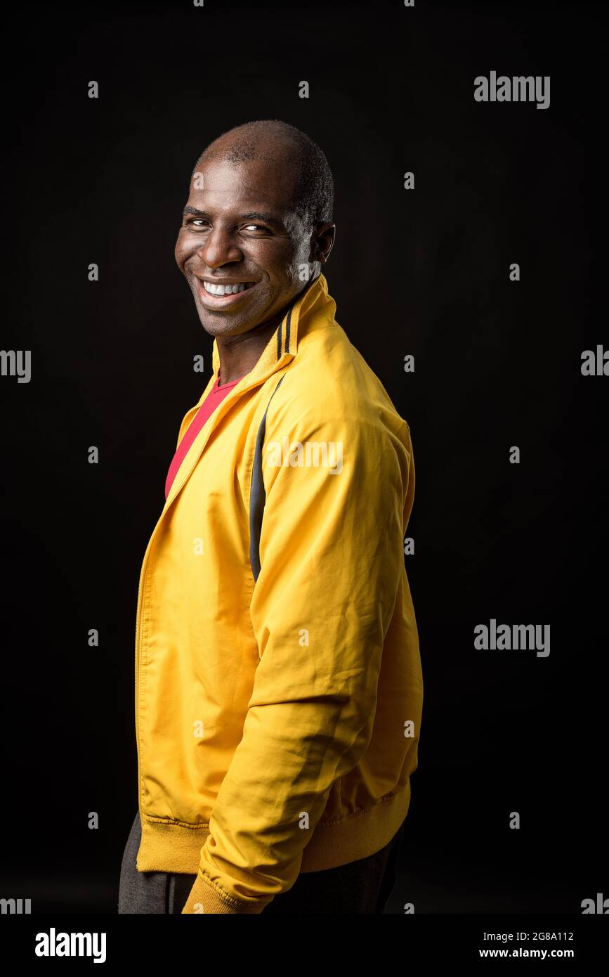 Side view of an African American man standing looking at camera and ...