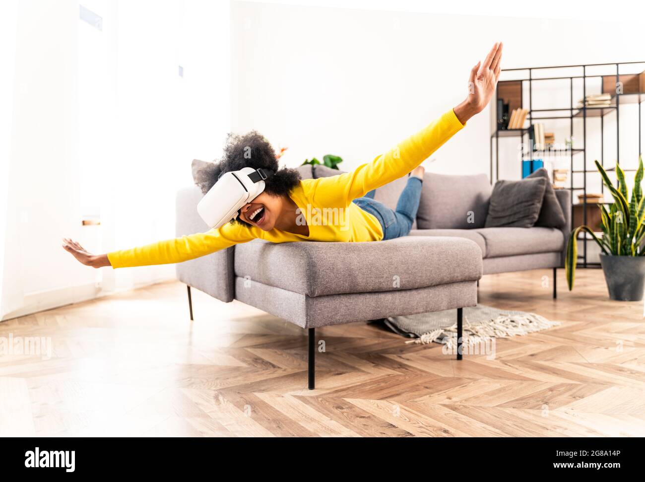 Beautiful woman playing at home with VR headset - Black woman lying ...