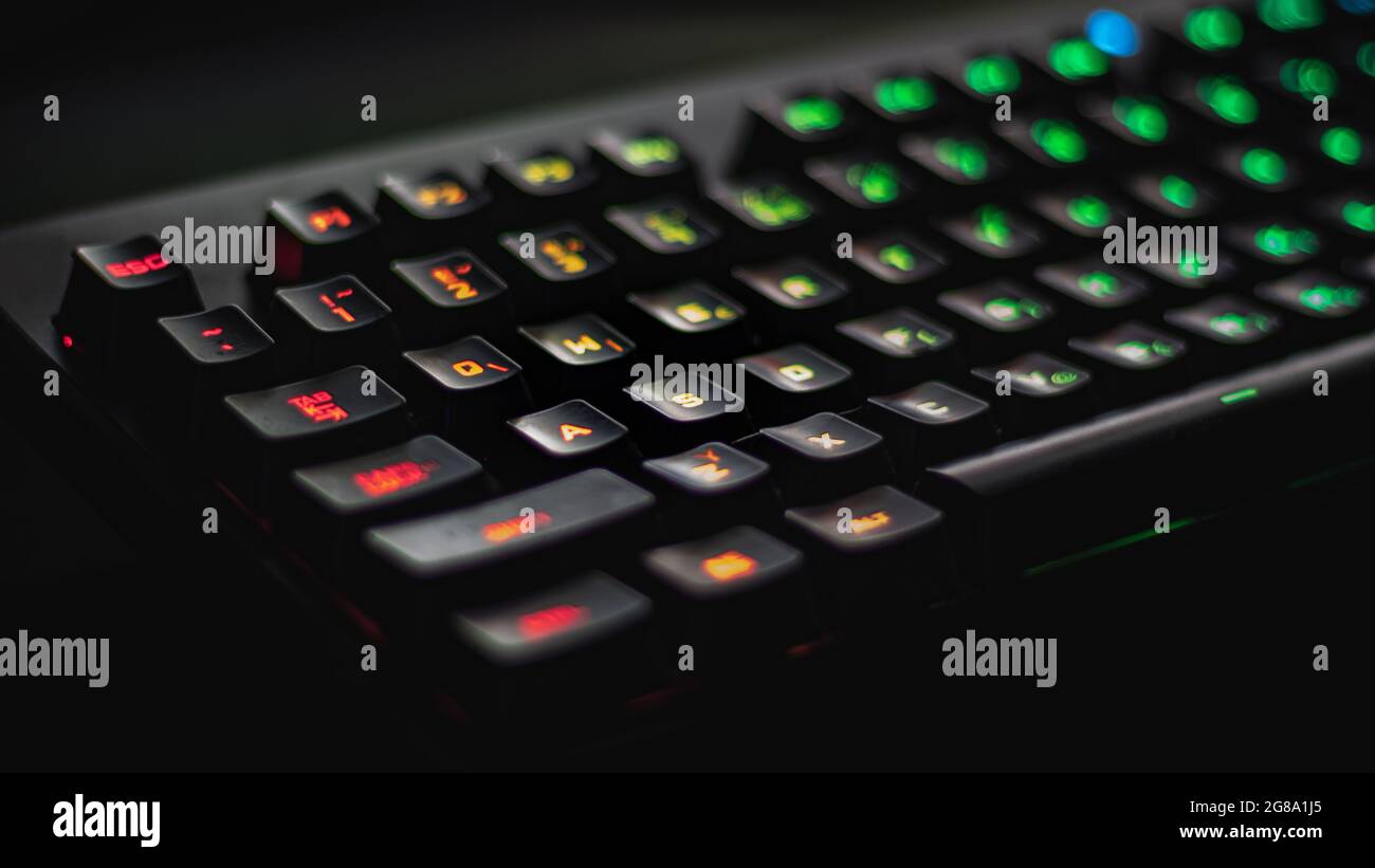 A closeup of a modern gaming keyboard with colorful lights on the table ...