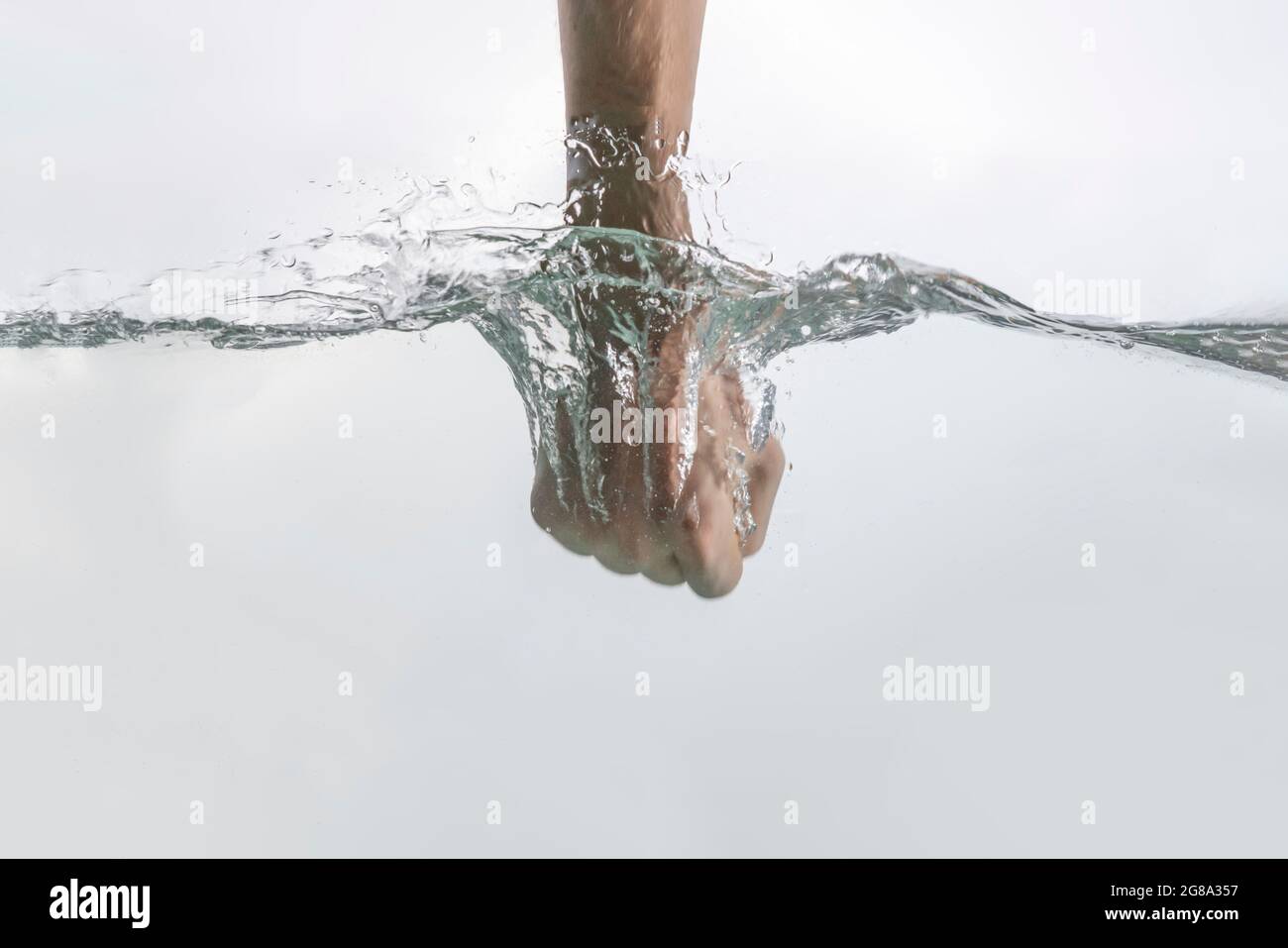 the male fist hand attack punch through the water surface, strength ...