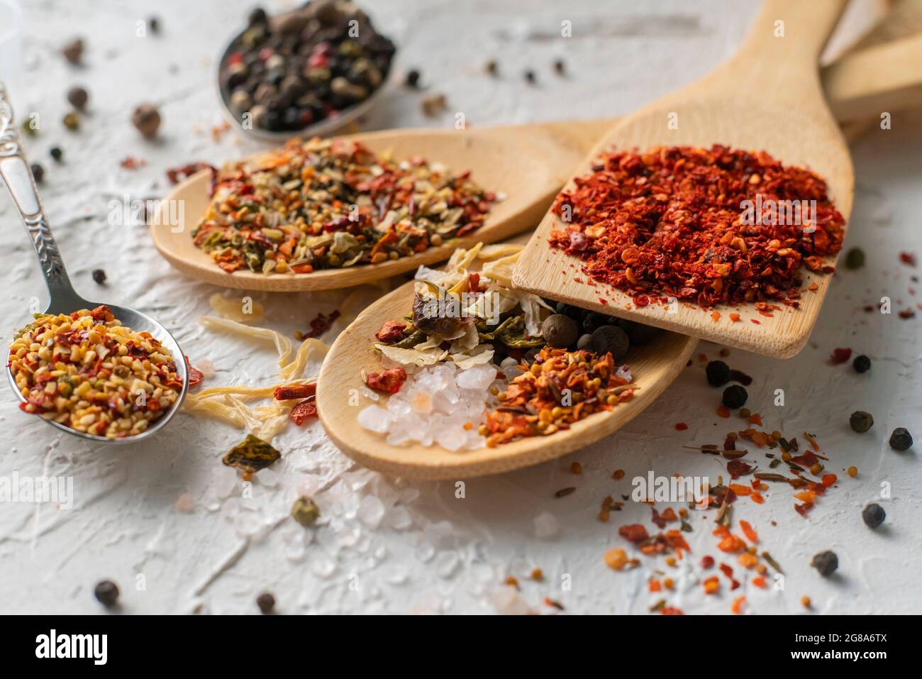 several spoons with mix variaty of different spices poured on the table ...