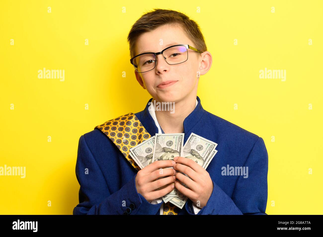 A boy in glasses and an oversized suit with a satisfied face is holding ...