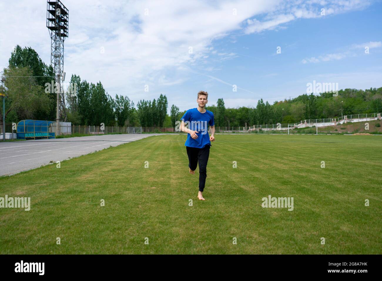 healthy morning running, male athlete on the green grass field with ...