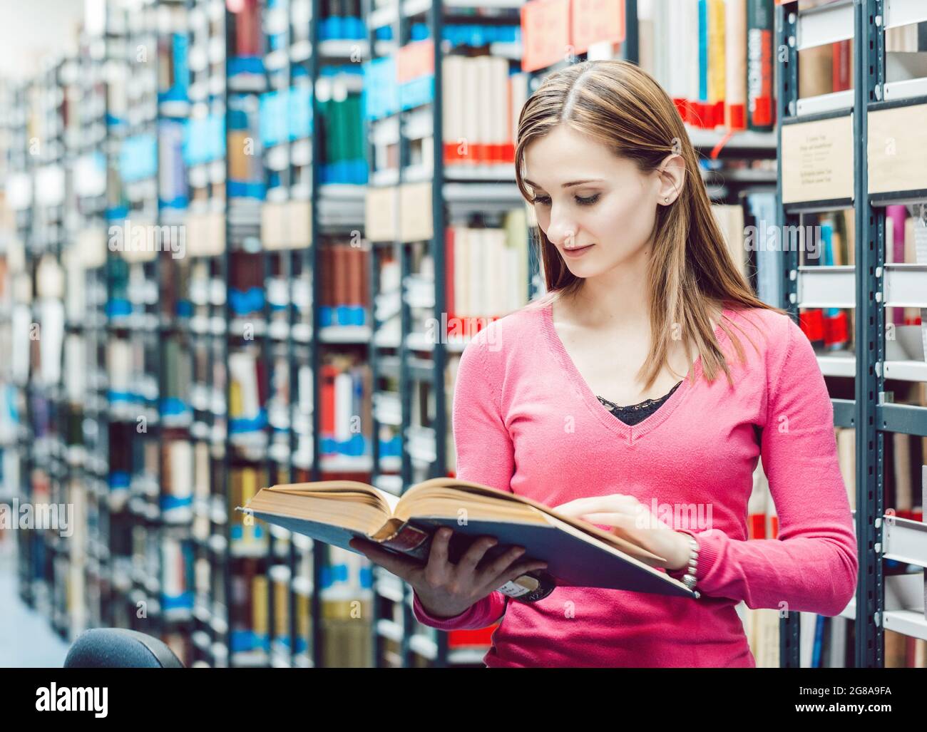 Student in college library reading a book Stock Photo - Alamy