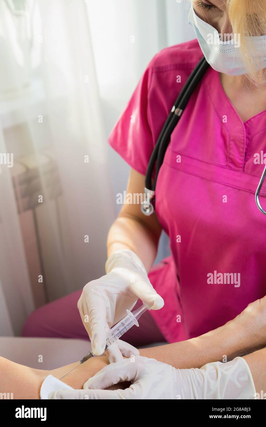 A girl doctor injects a syringe on her arm into a vein of an adult ...