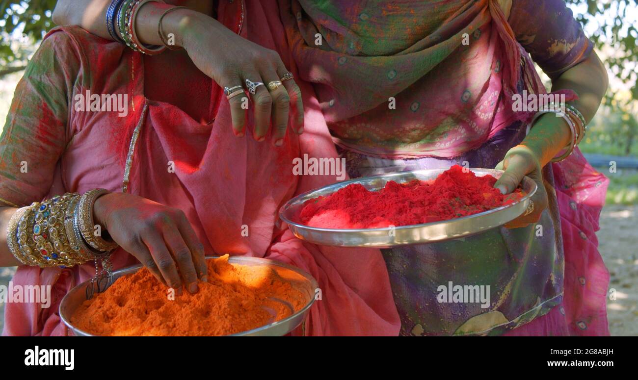 Metal platters with red and orange powder paint in female hands; Holi ...