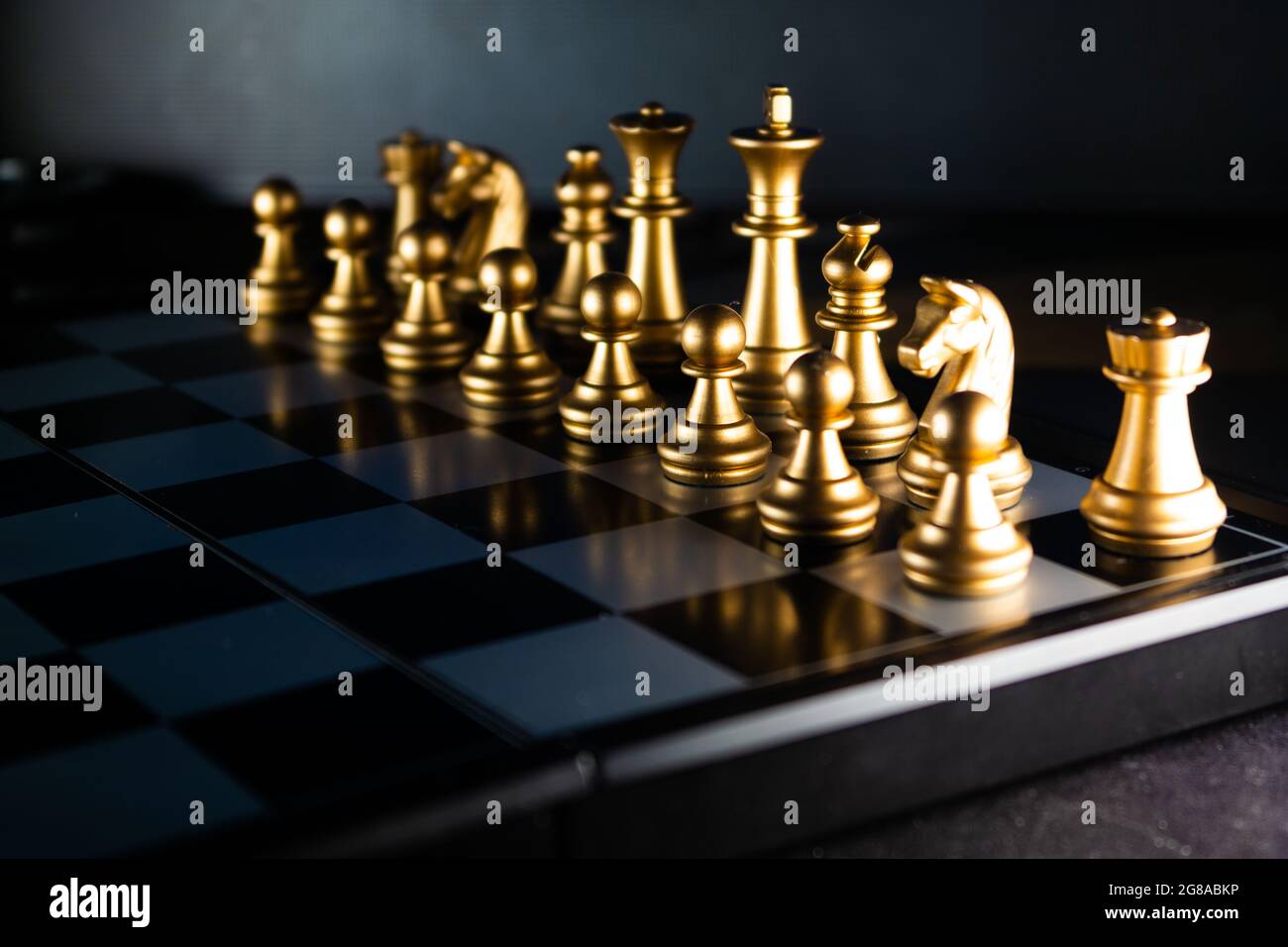 A horizontal shot of cool gold chess pieces in the starting position ...