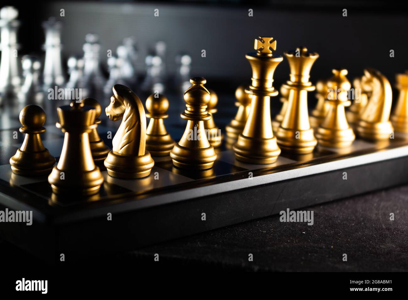 A horizontal shot of cool gold chess pieces in the starting position ...