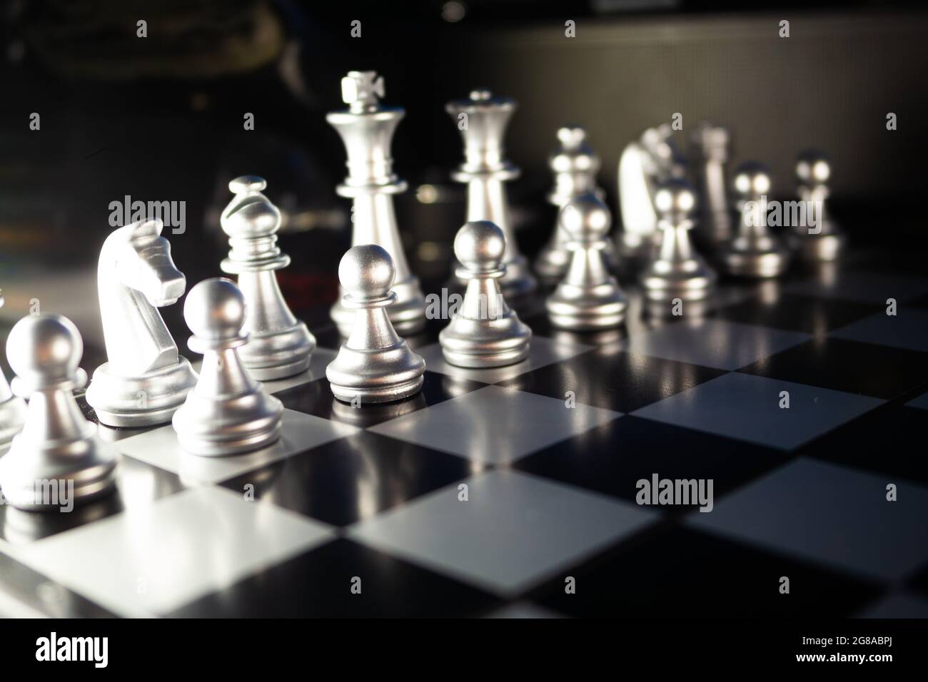 A horizontal shot of cool silver chess pieces in the starting position ...
