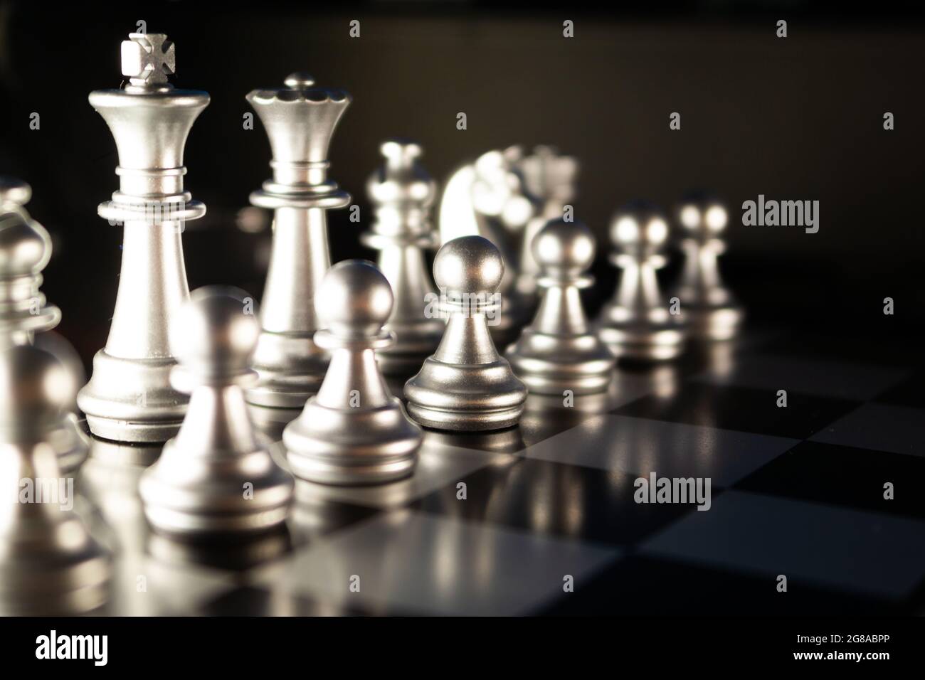 A horizontal shot of cool silver chess pieces in the starting position ...