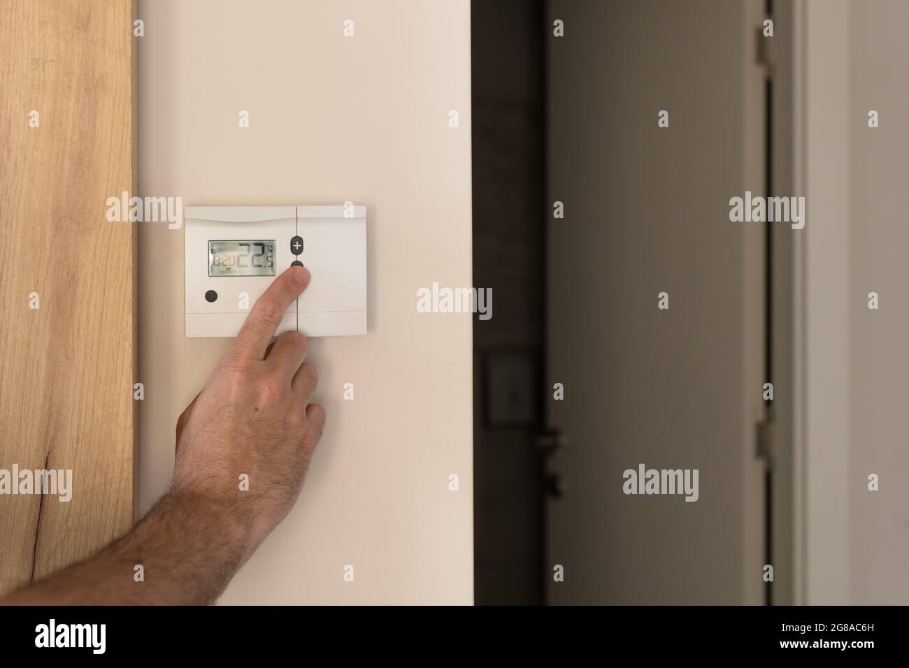 Male hand pushing the button of home heating and cooling system control ...
