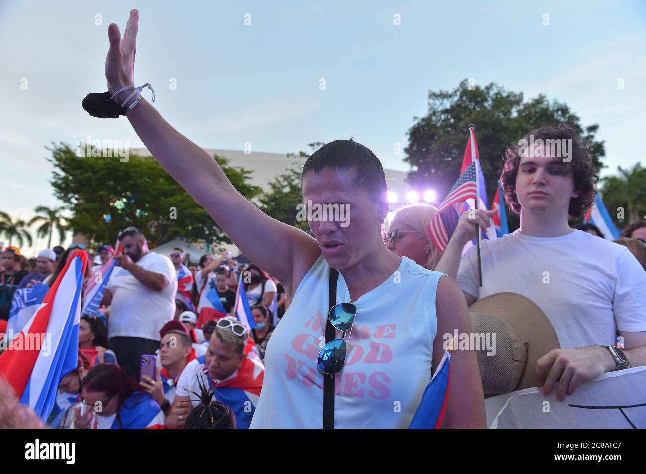 MIAMI, FLORIDA - JULY 17: People kneel down for a prayer, wave Cuban ...