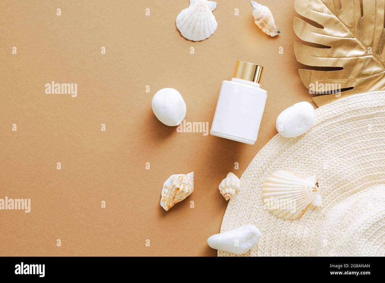 Sunscreen lotion, seashells, straw hat on sandy color background. Flay ...