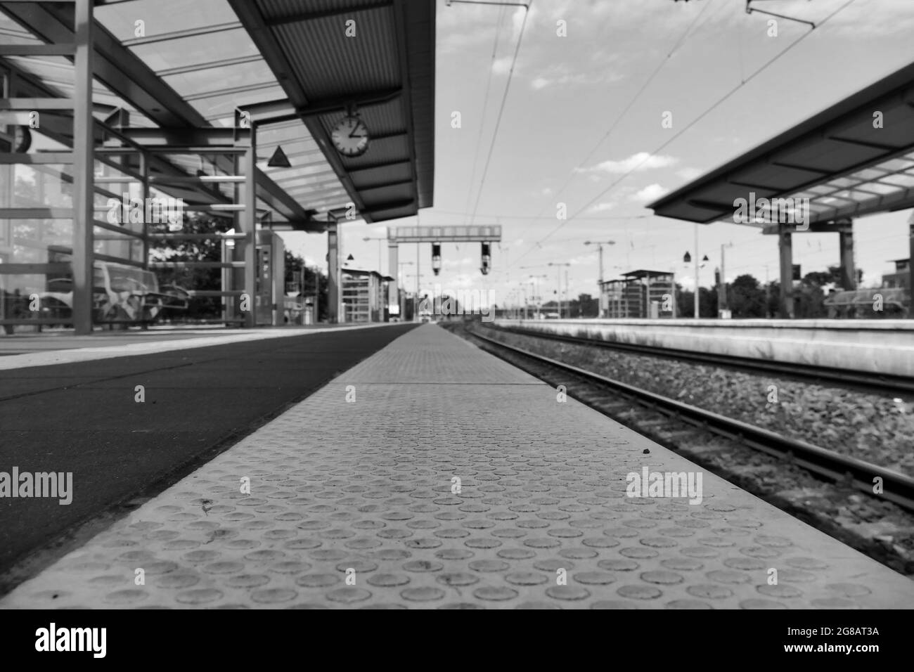 Grayscale shot of the paved ground next to a railway at a train station ...