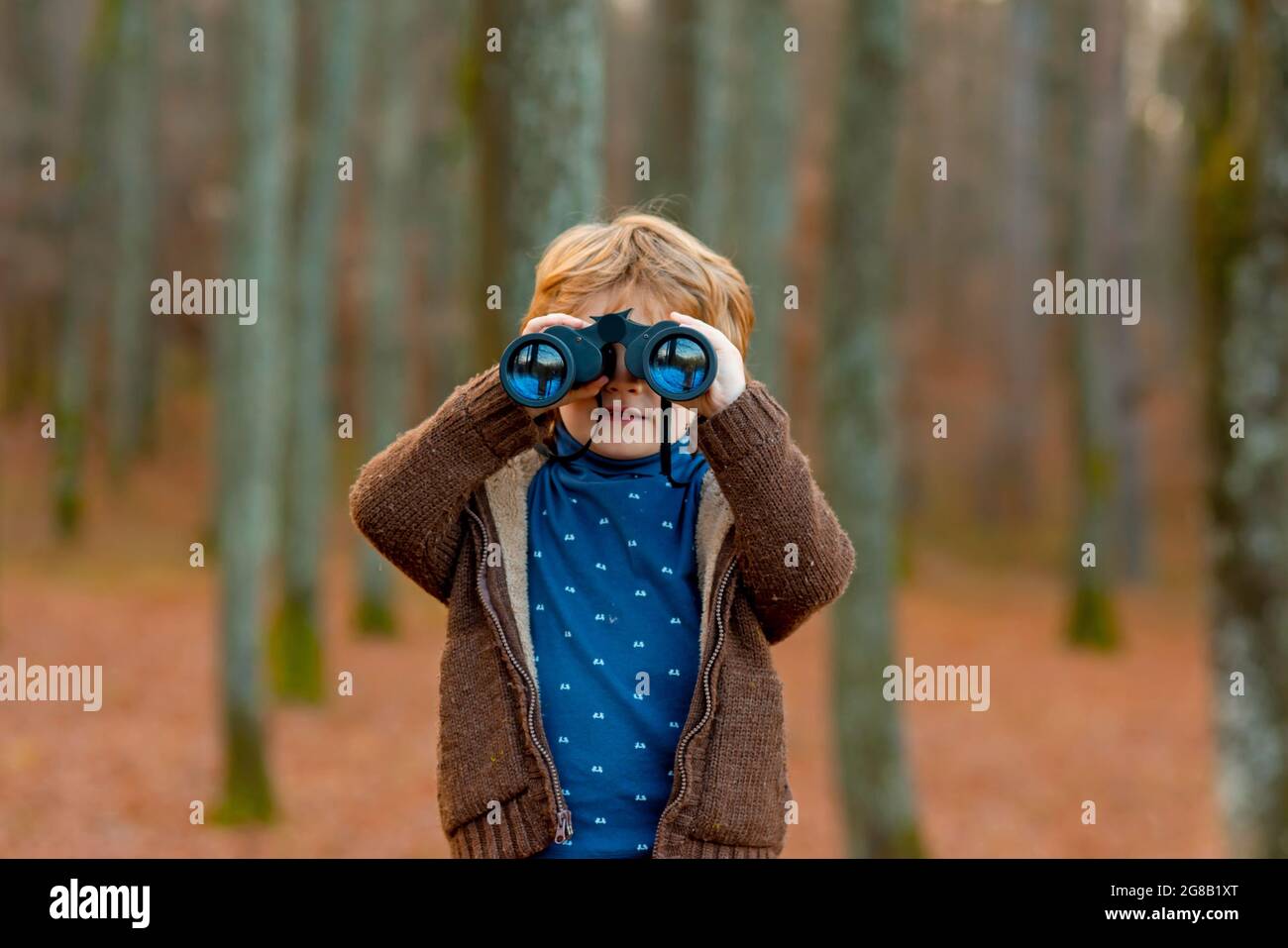 Kid looking through binoculars in forest. Child playing outdoors. Kids ...