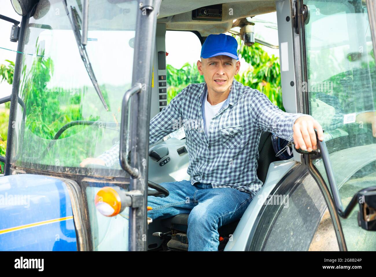 Skilled male farmer working on farm tractor in orchard Stock Photo - Alamy