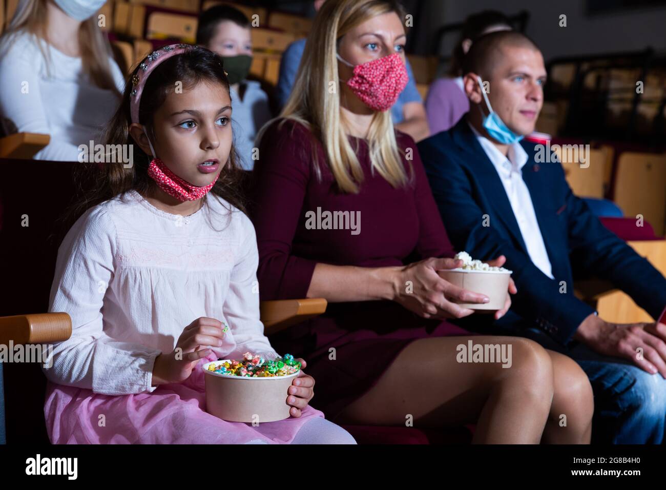 Preteen girl in protective mask watching movie in cinema Stock Photo ...