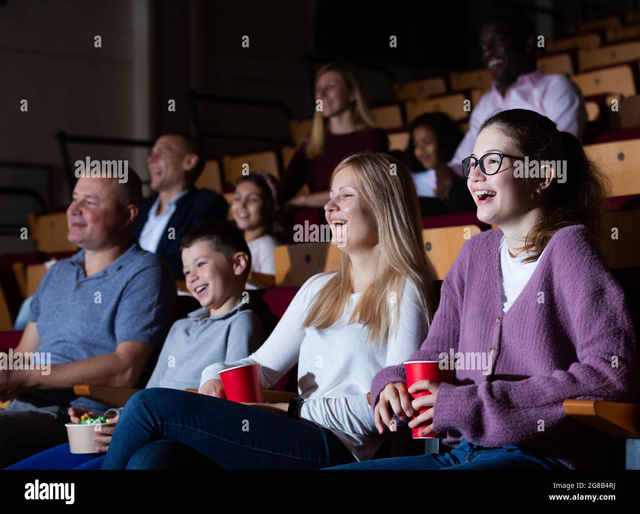 Cheerful parents with tween children watching comedy in cinema Stock ...