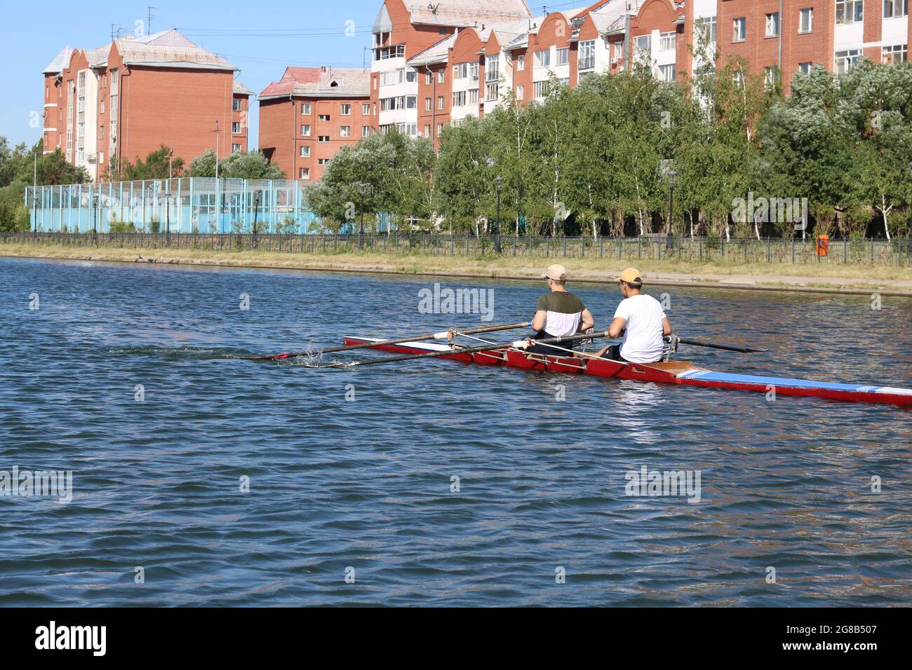Two boys rowing in boat in city river Stock Photo - Alamy