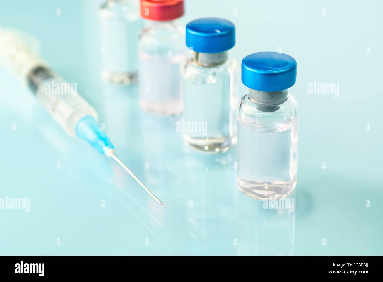 Group of vials with medication and syringe on table on blue background ...