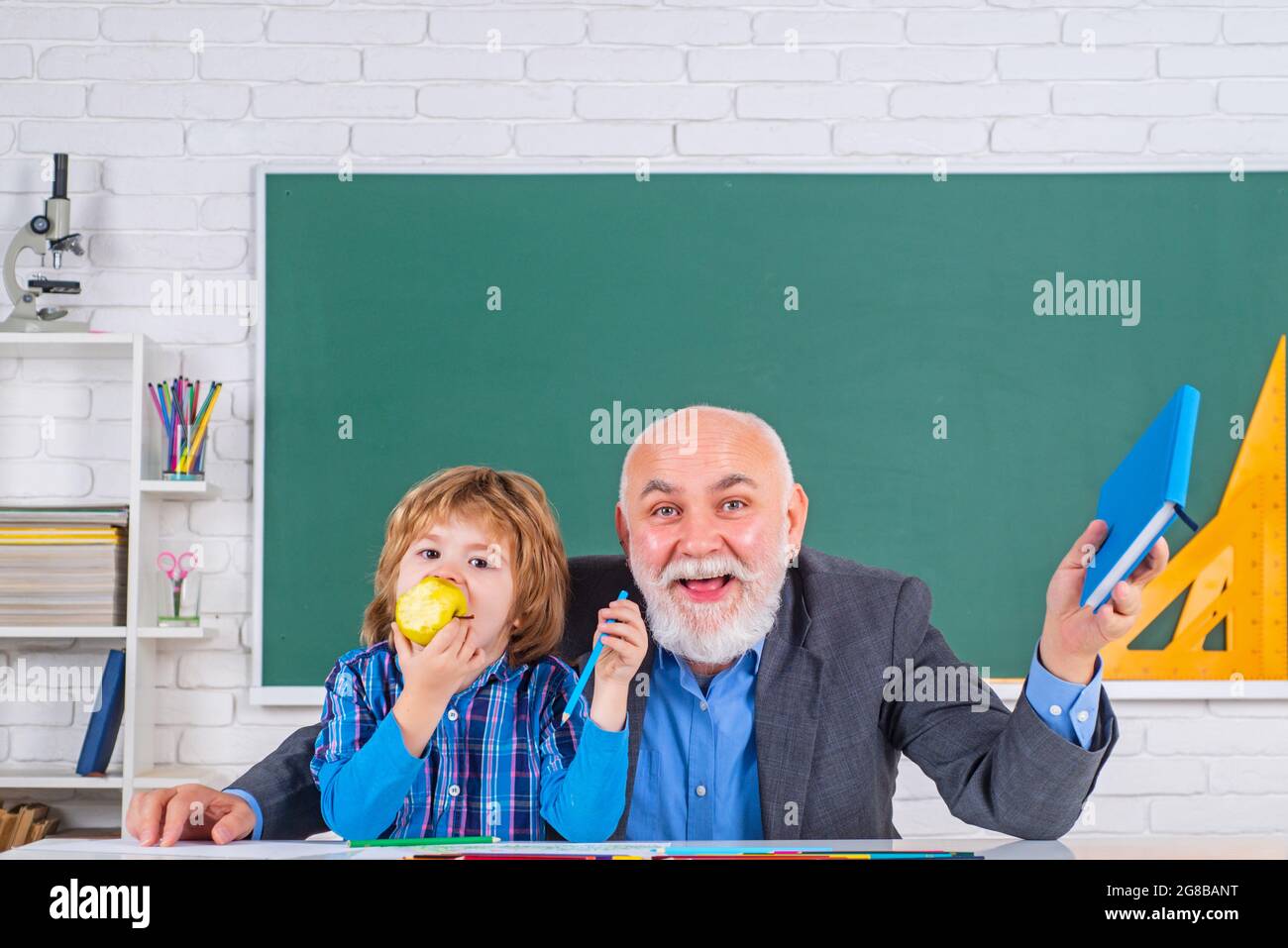 Professor and pupil in classroom at the elementary school. Senior ...