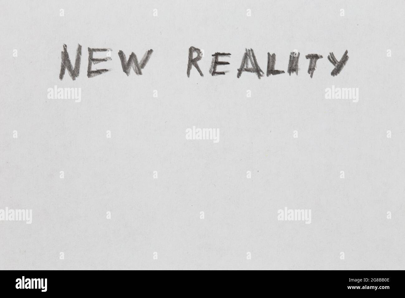 the words new reality handwritten on blank white paper with pencil ...