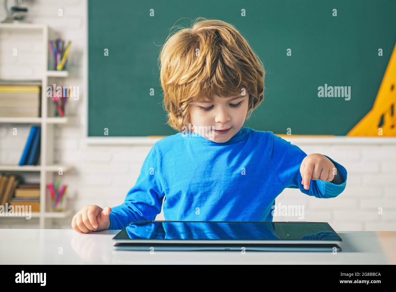 Pupil in class using digital tablet. Schoolboy with digital tablet in ...