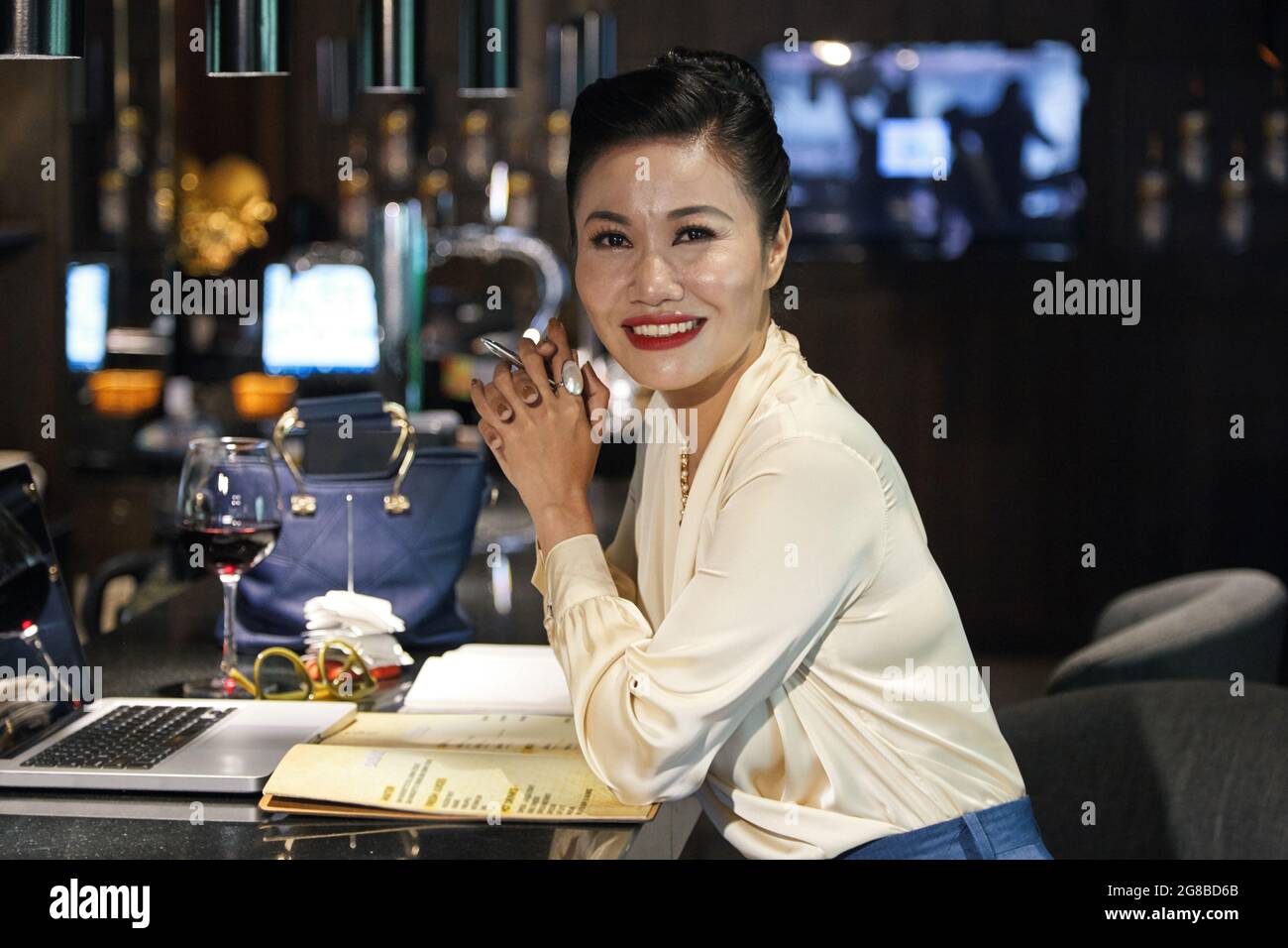 Beautful smiling female restaurant manager working on new menu, she is ...