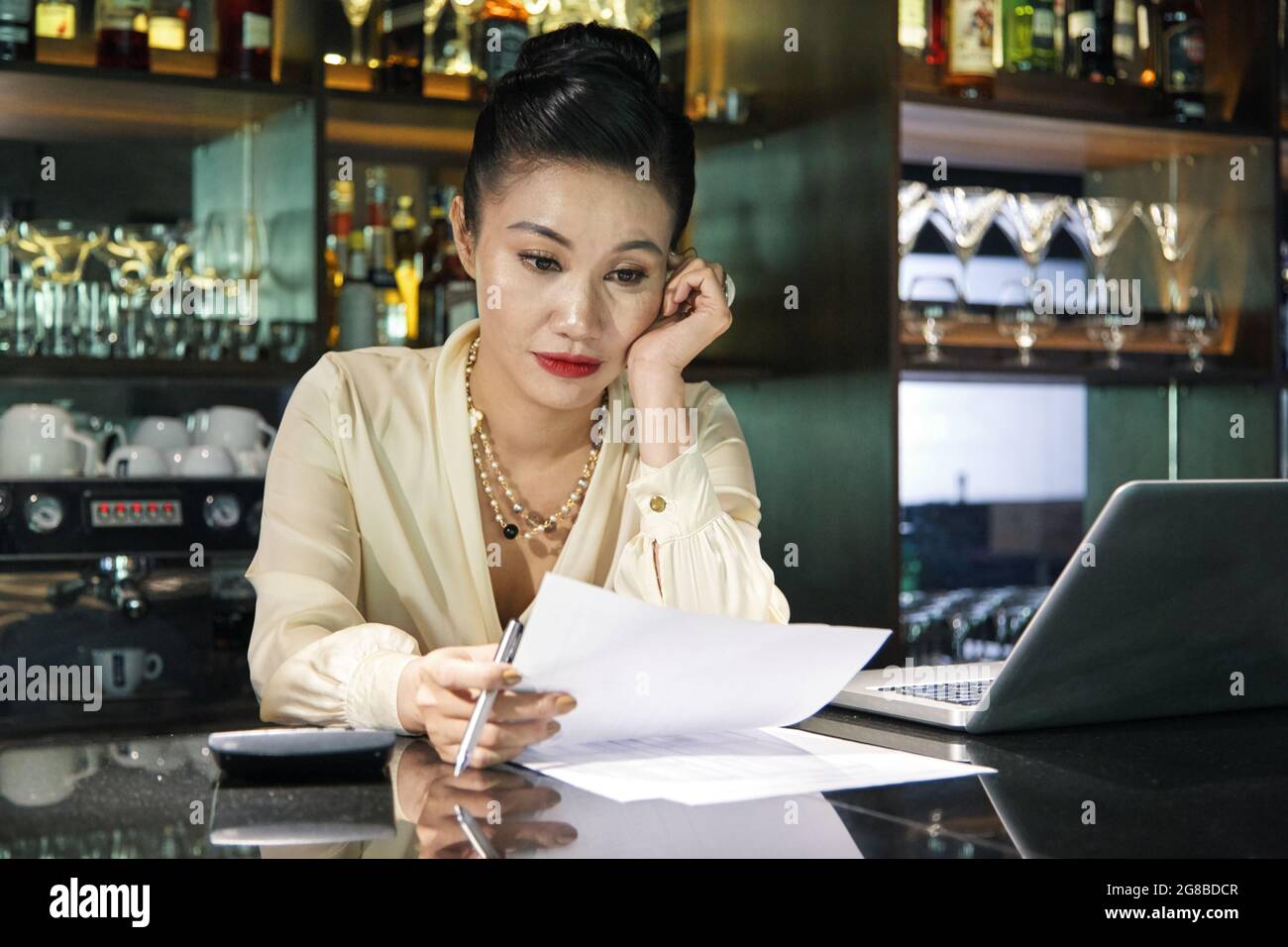 Pensive tired bar and restaurant owner reading sales report and ...
