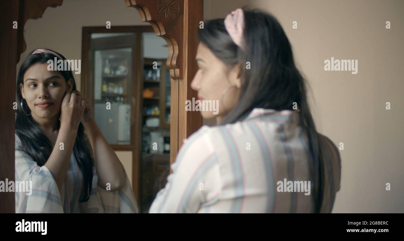 Pretty Indian woman getting ready for a date in front of the mirror ...