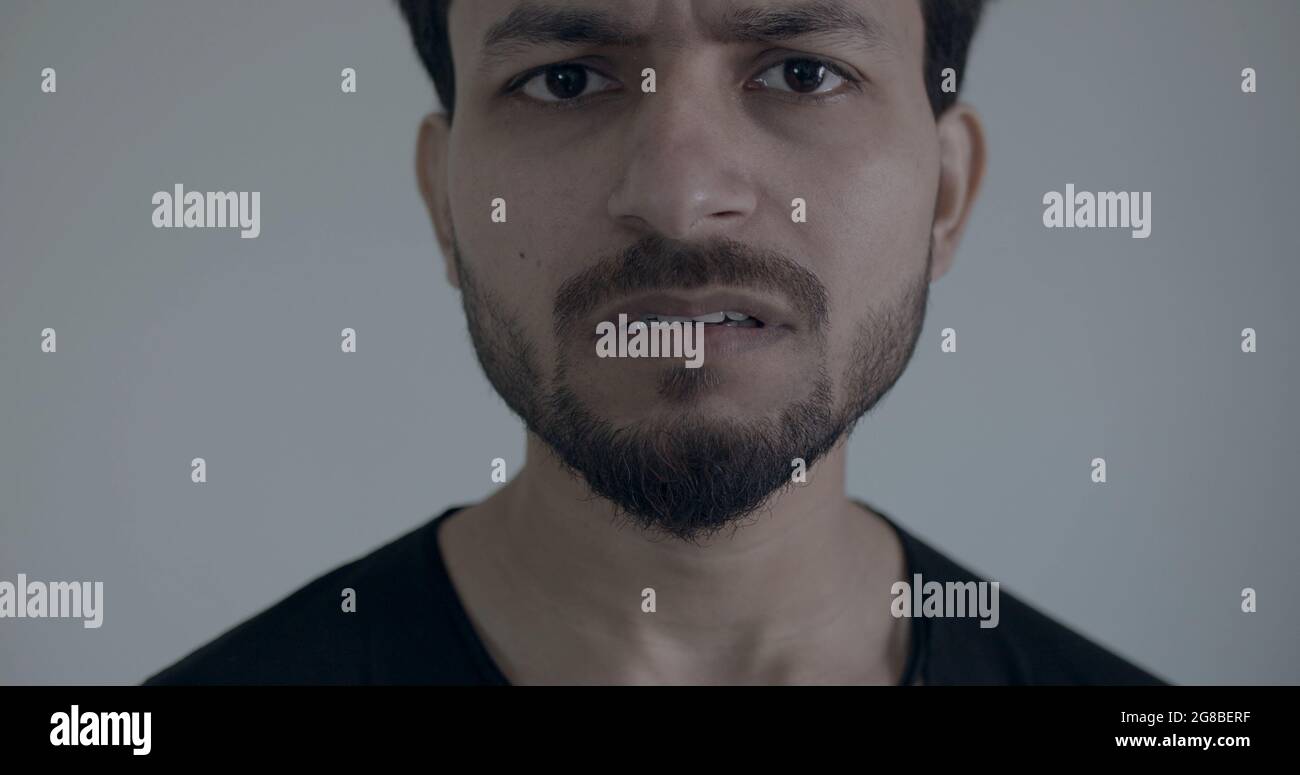 Sad bearded Indian guy experiencing failure on a white wall background ...