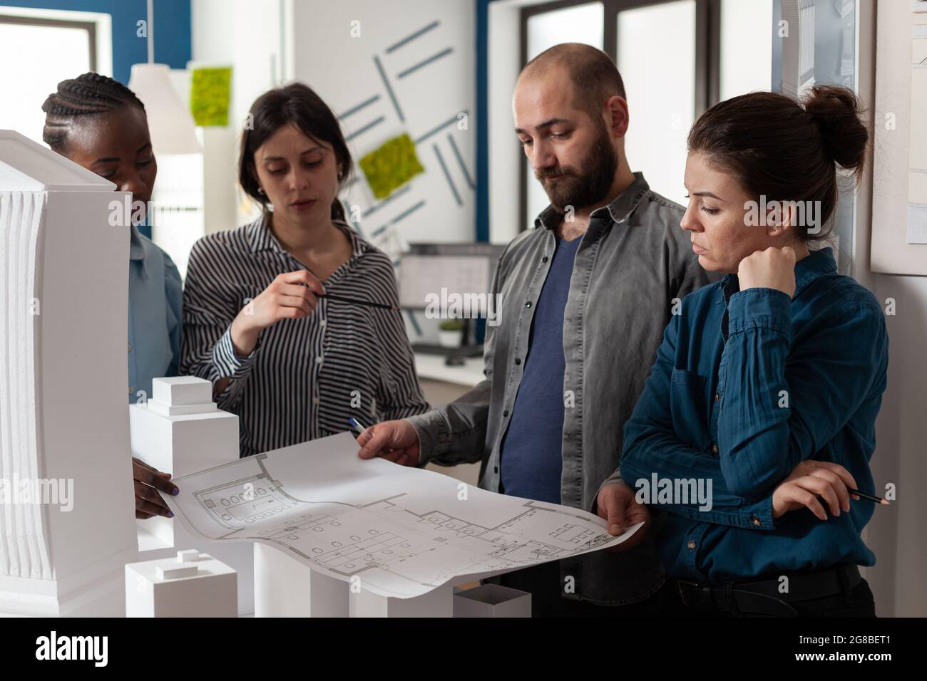 Team of multi ethnic architects designing blueprint plan for ...