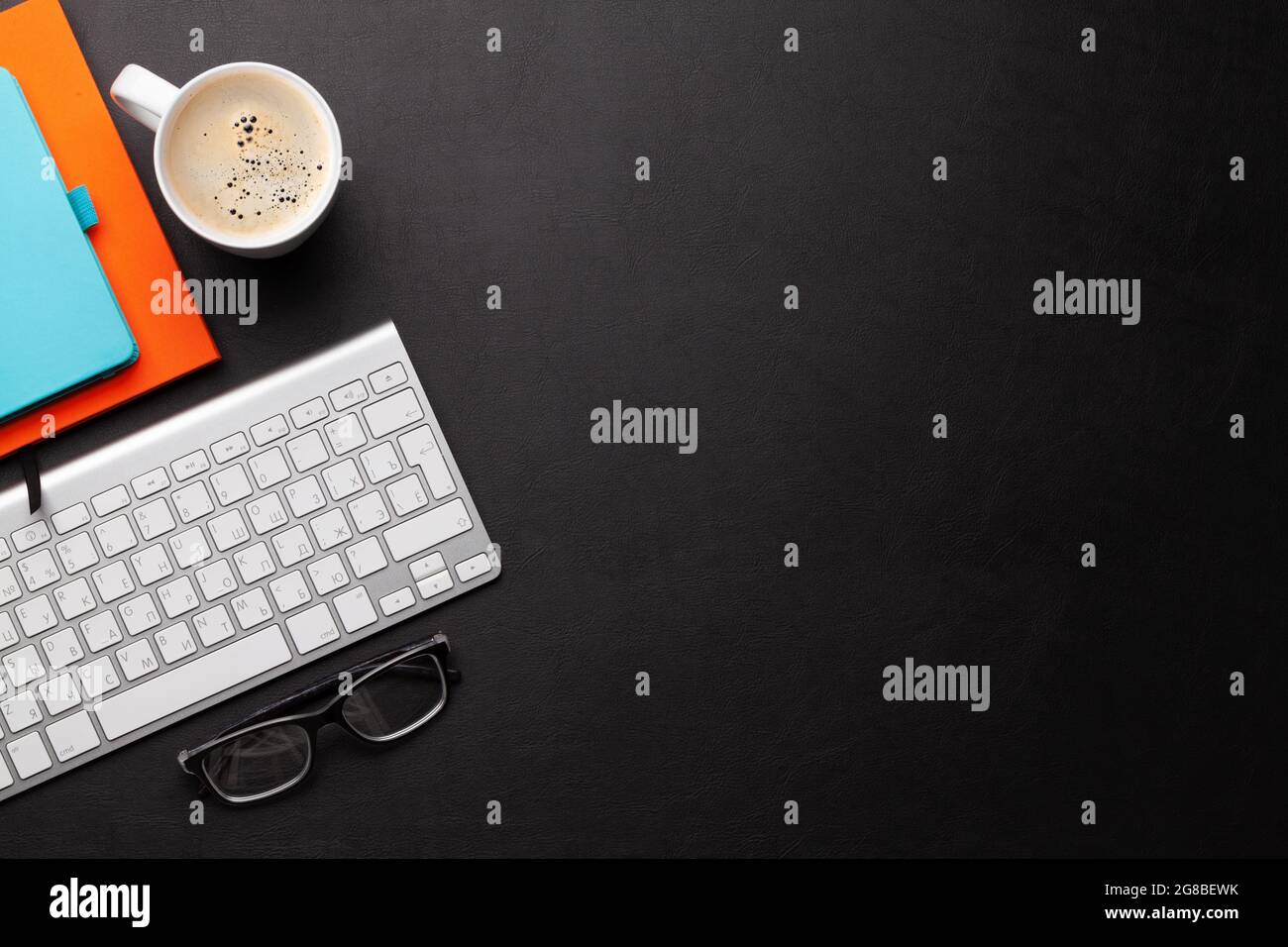 Office desk with supplies and coffee cup over black leather table. Top ...