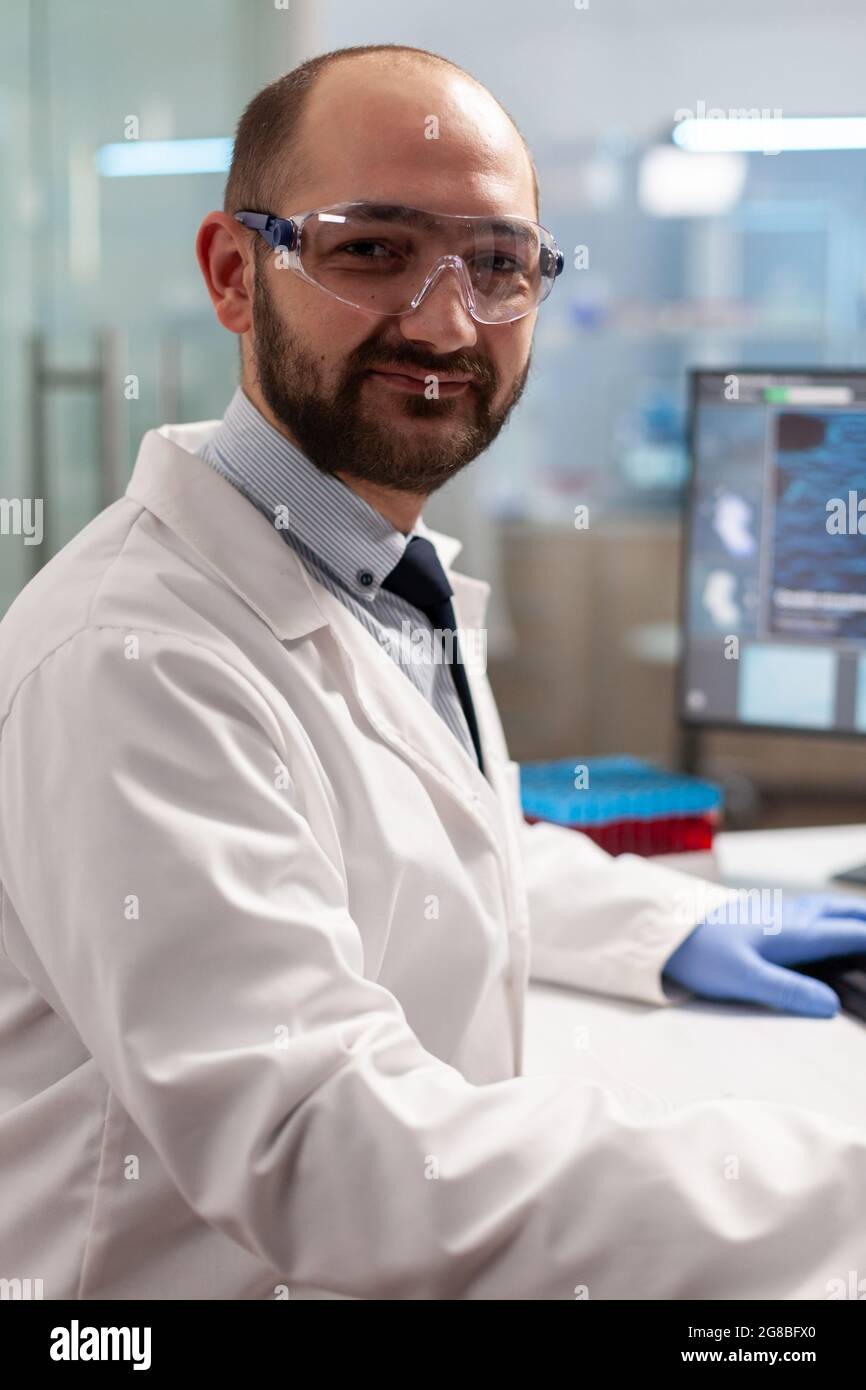 Microbiology virus researcher looking at camera in chemical lab smiling ...