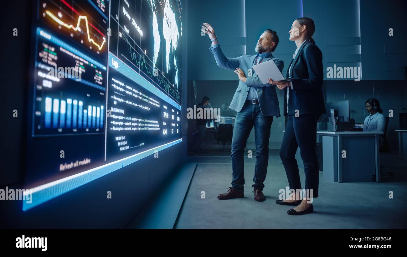 Project Manager and Computer Science Engineer Talk while Using Big Screen Display and a Laptop ...