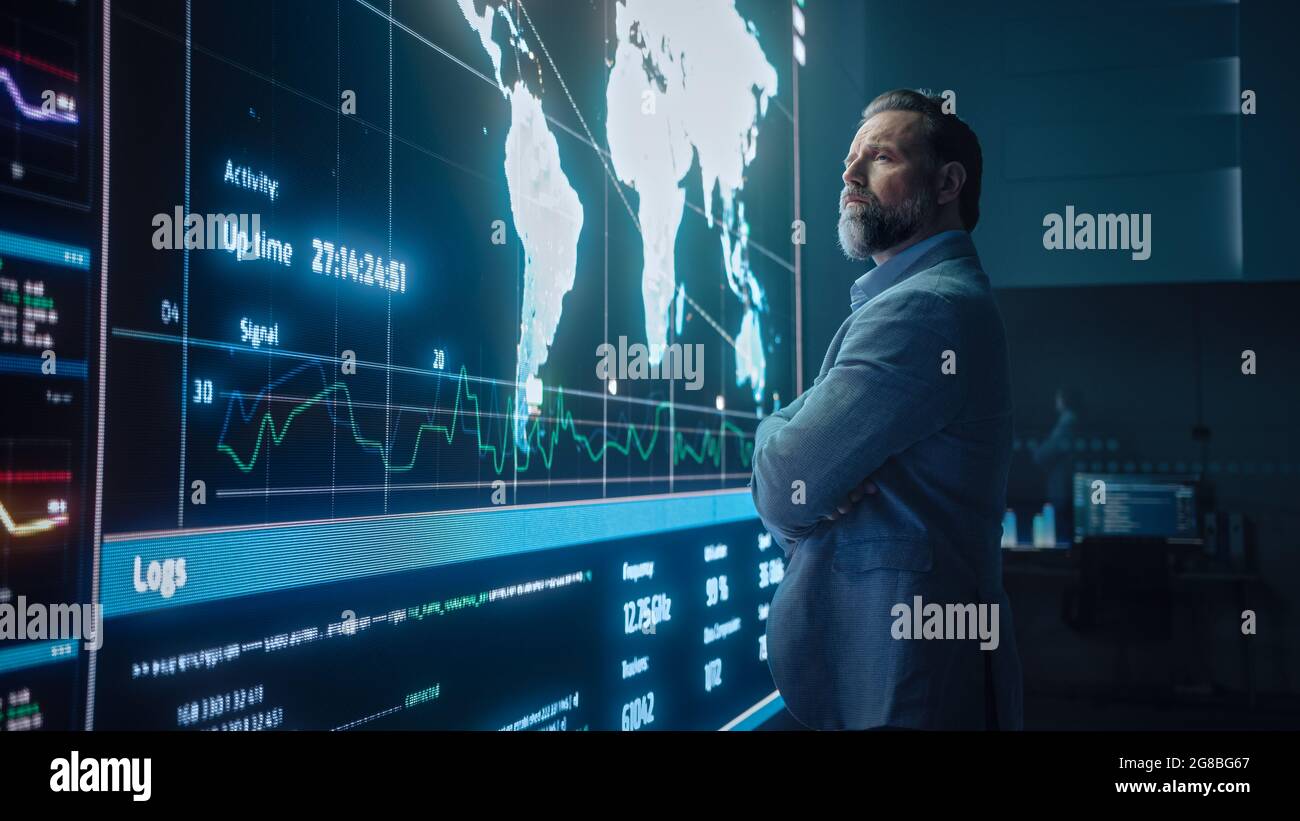 Senior Computer Science Engineer Looking at Big Screen Display Showing Global Map with Data ...