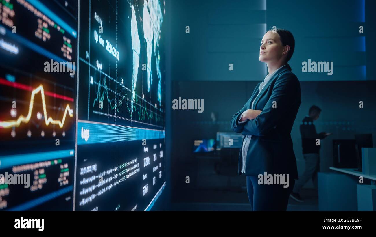 Young Female Computer Science Engineer Looking at Big Screen Display Showing Global Map with ...