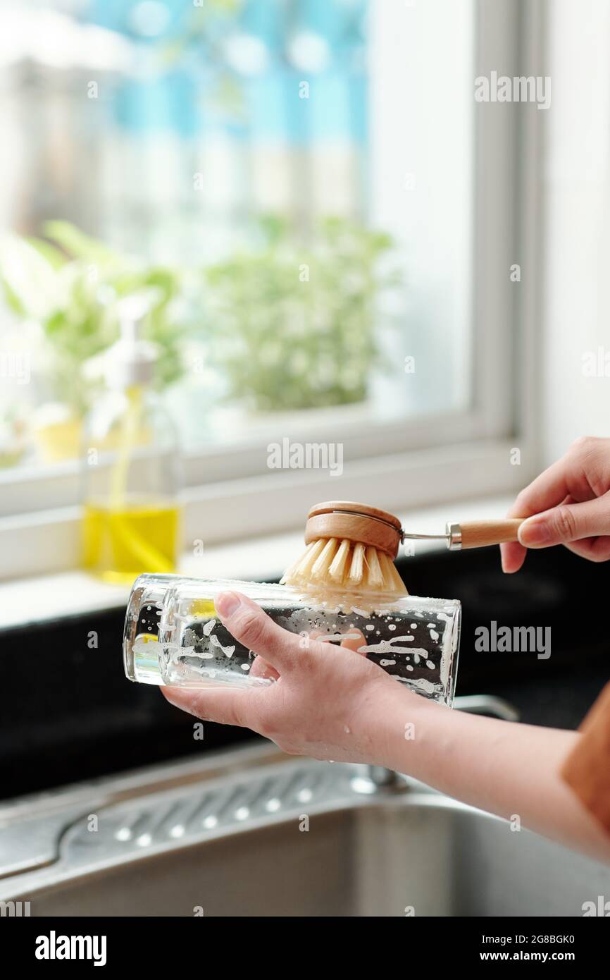 Hands of young woman washing dishes with dishwashing liquid and brush ...