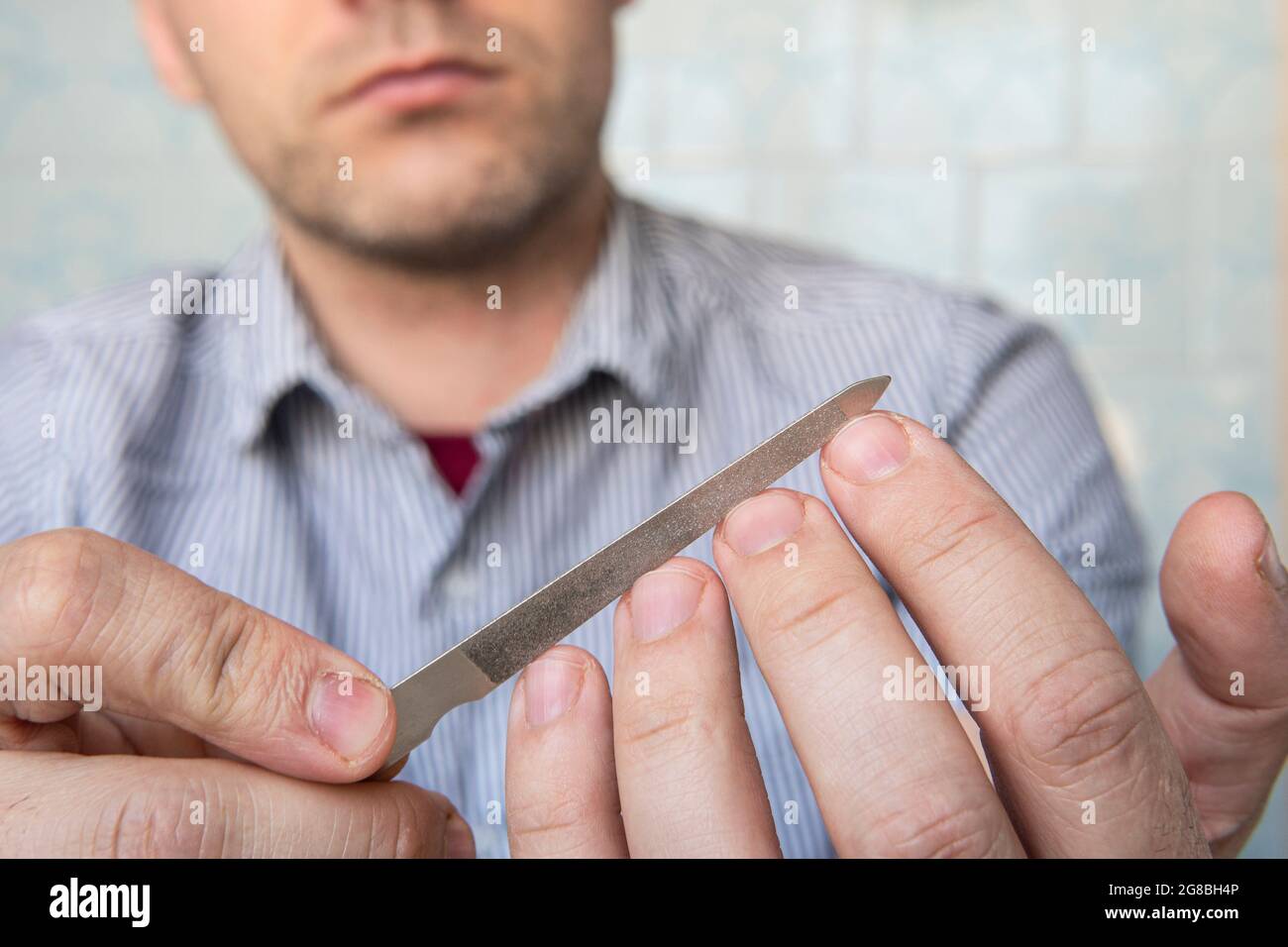A man uses a nail file to trim his nails on his hand. Close-up ...