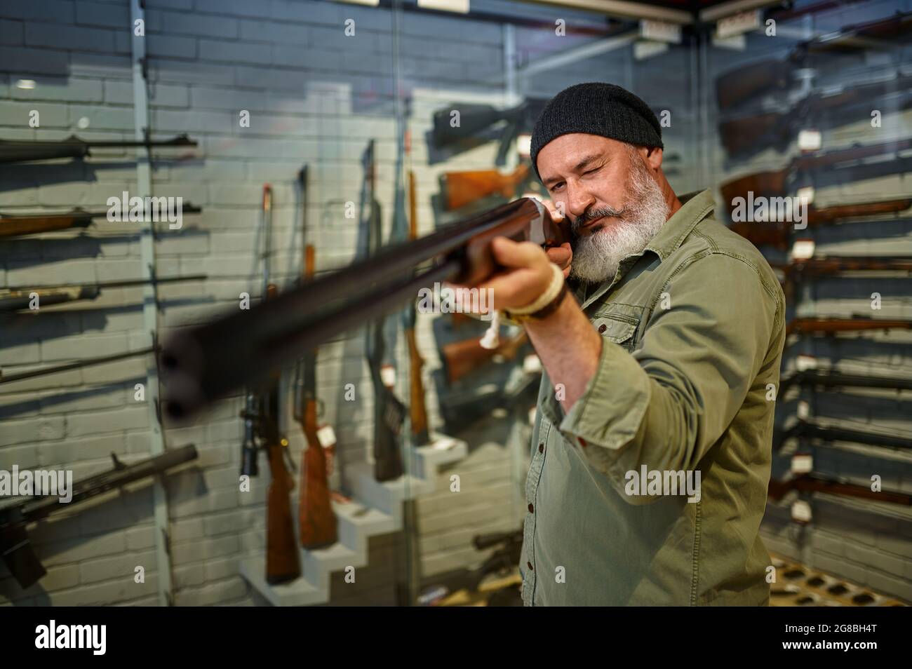 Bearded hunter choosing hunting rifle in gun store Stock Photo - Alamy