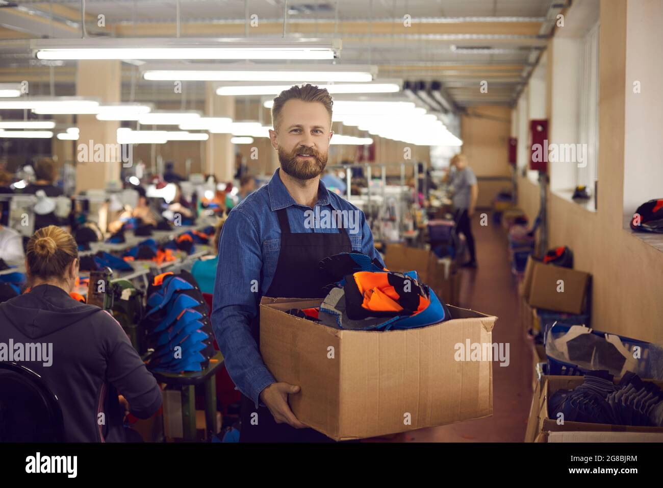 Portrait of male cobbler holding box at traditional shoe workshop ...