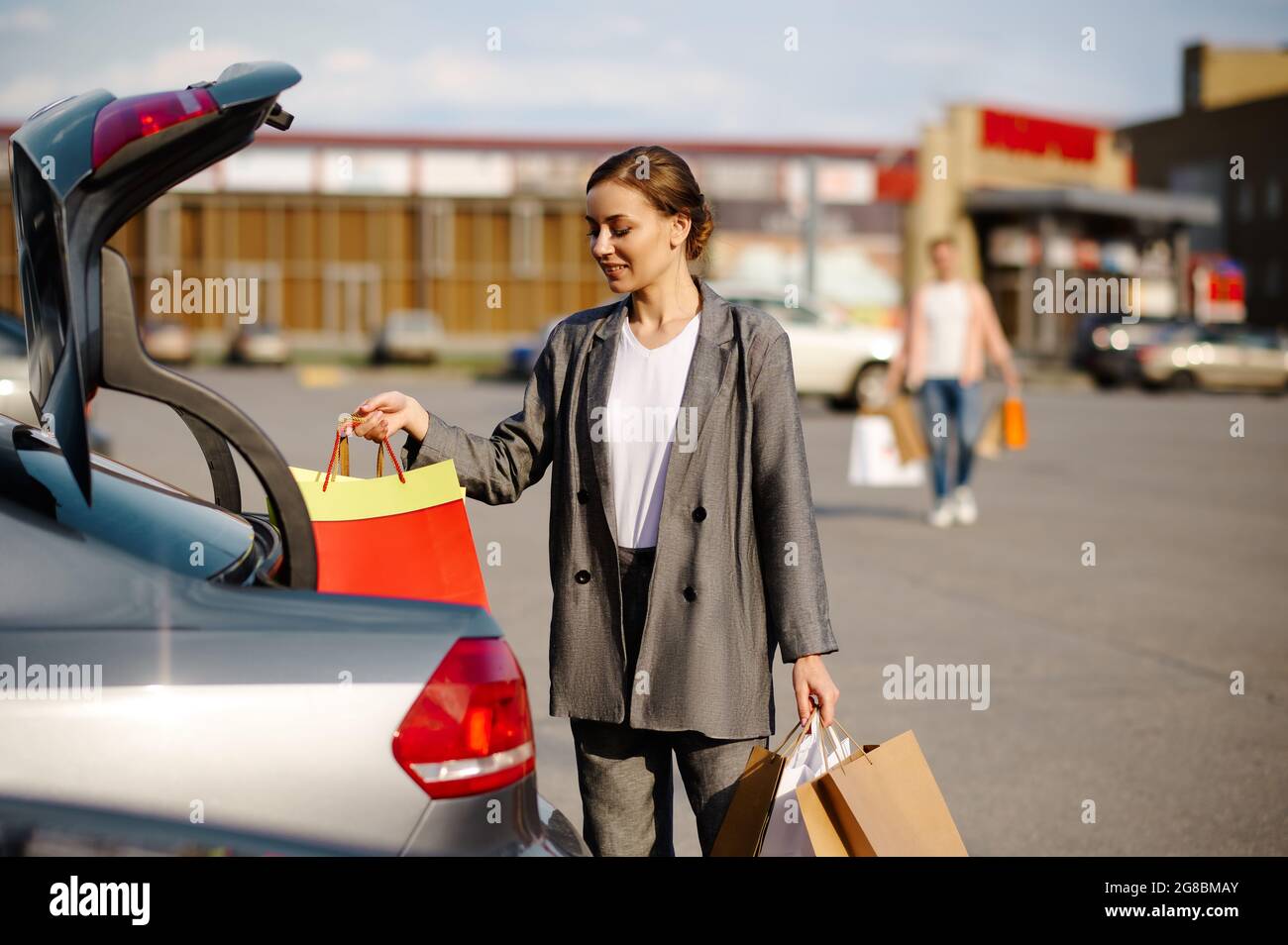 Woman puts her purchases in the trunk on parking Stock Photo - Alamy